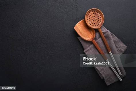 어두운 돌 배경에 나무기구 바질 잎 및 향신료를 요리합니다 추상적 인 음식 배경 나무 요리 숟가락 프레임이있는 어두운 소박한 주방 테이블의 상단보기 당신의 디자인을 위한