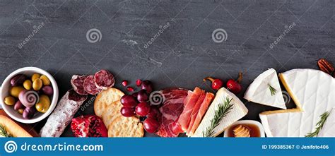 Assortment Of Cheese And Meat Appetizers Bottom Border On A Slate Stone Banner Background
