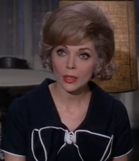A Woman With Blonde Hair Wearing A Black Shirt And White Trim On Her