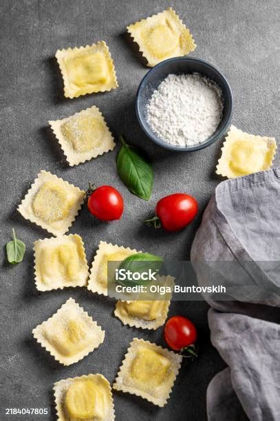 밀가루와 냅킨으로 어두운 배경에 토마토와 바질을 곁들인 파스타 라비올리 전통적인 수제 이탈리아 음식 개념입니다 가득 찬에 대한