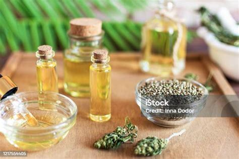 Botol Minyak Rami Dengan Biji Ganja Dan Daun Kering Di Atas Meja Kayu