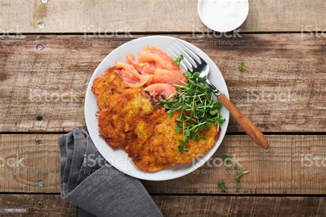 감자 팬케이크 오래된 나무 테이블 배경에 소박한 접시에 크림 파 마이크로 그린 붉은 연어와 소스와 함께 집에서 만든 감자 팬케이크 또는 라켓 튀김 소박한 스타일 맨 위