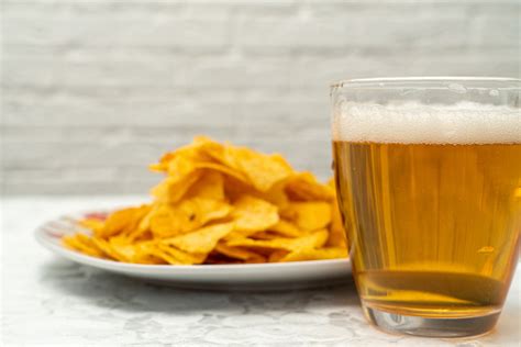 차가운 맥주 한 잔과 접시에 매운 감자 칩이 많이 있는데 건강에 해로운 음식 0명에 대한 스톡 사진 및 기타 이미지 0명