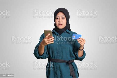 히잡을 쓴 쾌활한 아시아 무슬림 여성의 초상화 휴대전화를 들고 신용카드를 보여준다 재정 및 저축 개념 흰색 배경에 격리된 이미지