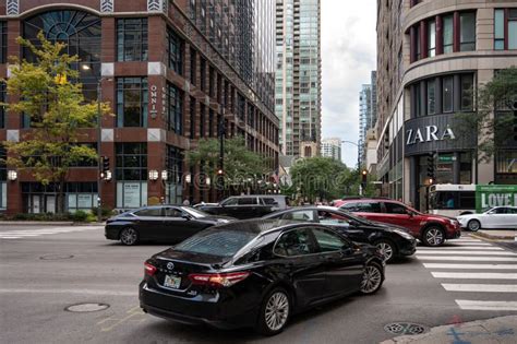 Fleet Of Vehicles Drive Down A Bustling City Street With The Zara And