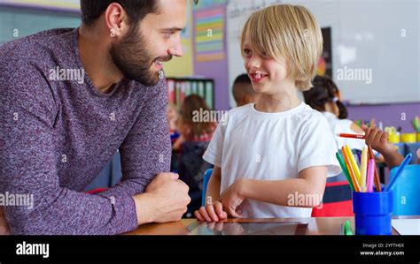 Elementary School Teacher And Male Pupil Drawing Using Digital Tablet