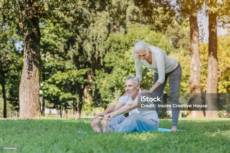 운동과 요가 운동을하는 동안 공원에서 성숙한 남자를 스트레칭하는 데 도움이 시니어 여성 2명에 대한 스톡 사진 및 기타 이미지 2명 건강한 생활방식 공원 Istock