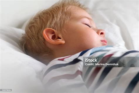 하얀 부드러운 담요 위에서 자고 있는 어린 아이 3살짜리 아이들은 아늑한 침실에서 혼자 잔다 부드러운 섬유 졸린 금발 머리 아기