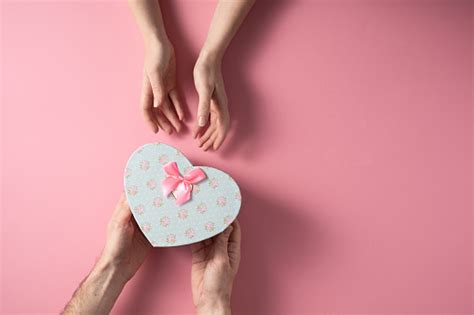 발렌타인 데이 축하 개념입니다 사랑하는 사람의 좋은 선물 섬세한 분홍색 배경에 남자와 여자의 활 손이 상자 공간을 복사합니다