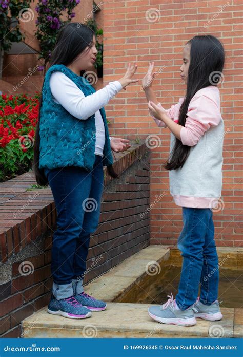 Two Colombian Latin American Girls Sitting In The Schoolyard Playing