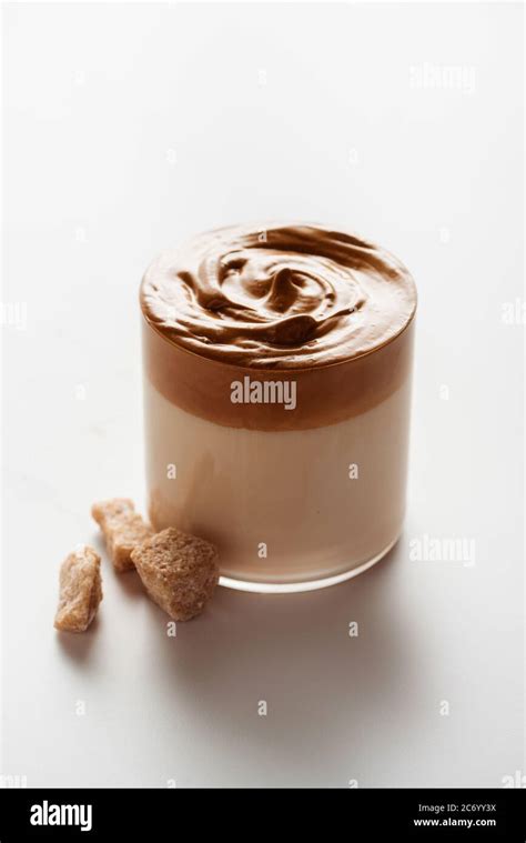 Delicious Dalgona Coffee In Glass Near Brown Sugar On White Background