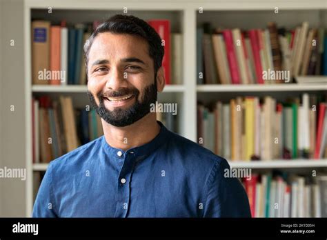 Happy Indian Business Man Teacher Standing In Front Of Bookshelves