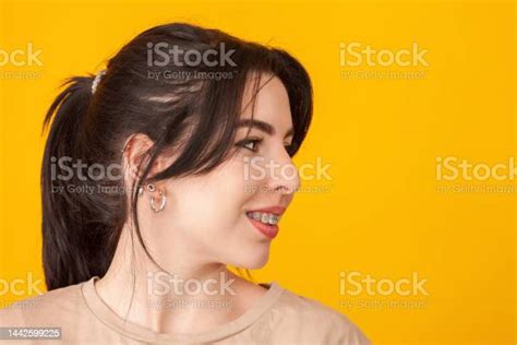 노란색 배경에 베이지색 티셔츠를 입고 검은 머리를 가진 쾌활한 20세 백인 여성의 클로즈업 스튜디오 초상화 20 24세에 대한