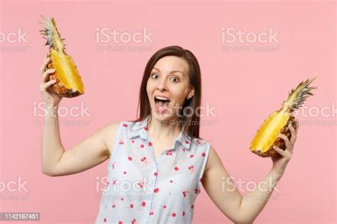 여름 옷을 입을 열어 분홍색 파스텔 배경에 고립 된 신선한 파인애플 과일의 Halfs를 유지 하는 젊은 여자 충격 사람들은 생생한 라이프 스타일 휴식 휴가 개념입니다 복사