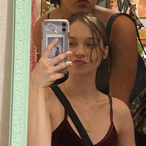 A Woman Taking A Selfie In Front Of A Mirror With Her Cell Phone Up To Her Face
