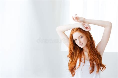 Красивая женщина при длинные красные волосы сидя в кровати Стоковое Изображение изображение