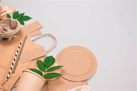 친환경 식기 세트 밝은 회색 배경 카피 스페이스에 크래프트 종이 식품 포장 길거리 음식은 종이 포장을 빼앗습니다 컵 접시 빨대 용기 녹색 잎이있는 종이 봉투 카드보드에 대한