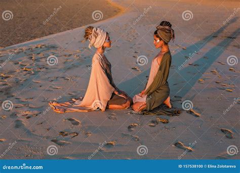 Deux Jeunes Filles Magnifiques Au Turban Assise Sur La Plage Au Coucher