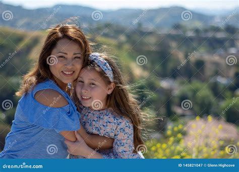 Latina Mother And Daughter Smiling And Laughing On A Hill In Front Of Yellow Flowers Stock Image