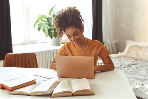Cheerful Young African American Female Student Sitting At Desk At Home