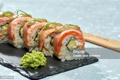 가벼운 배경에 검은 접시에 훈제 연어 아보카도 크림 치즈와 달콤한 소스를 가진 필라델피아 초밥 롤 0명에 대한 스톡 사진 및