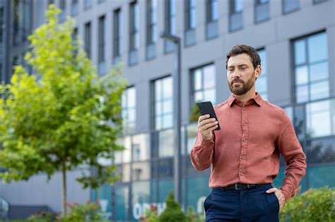 도시 환경에서 현대적인 사무실 건물 근처에서 야외에서 스마트 폰을 사용하는 자신감 넘치는 사업가 Brand Name Smart Phone에 대한 스톡 사진 및 기타 이미지