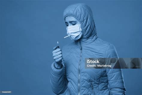 의료 용 보호 마스크를 착용한 어린 소녀가 마스크를 통해 입에 담배를 들고 불을 밝힙입니다 20 24세에 대한 스톡 사진 및 기타 이미지 Istock