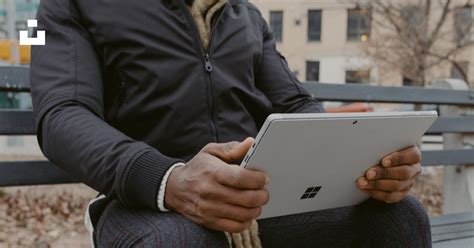 검은 재킷과 회색 바지를 입은 사람이 은색 표면을 들고 벤치에 앉아 있다 사진 Unsplash의 무료 컴퓨터 이미지