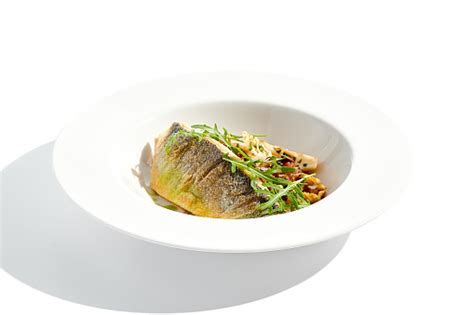 흰색 배경에 고립 된 야채로 흰 생선을 구워냅니다 바삭한 피부와 토마토 샐러드를 곁들인 넙치 그릴 야채가있는 생선 필레는