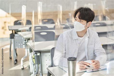전염병 상황에 마스크 쓰고 강의실에서 공부 또는 수업을 듣고 있는 아시아 대한민국 대학생 남자 모델 Stock Foto