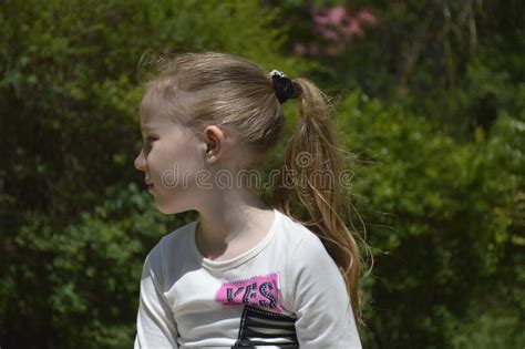 Beautiful Girl Sits On A Bench In The Park And Breathes Fresh Air Stock