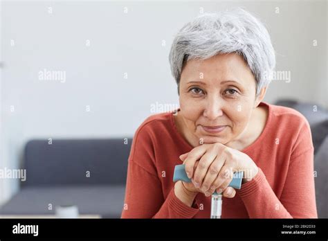 Portrait Of Senior Woman With Grey Hair Looking At Camera While Sitting