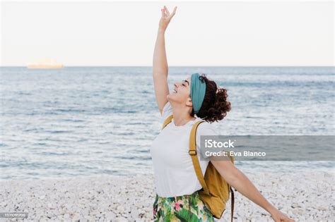 일몰 동안 해변에서 노란 배낭과 팔을 들고 행복한 백인 여성 여름 시간 공상 야외 라이프스타일 30 34세에 대한 스톡 사진 및 기타 이미지 Istock