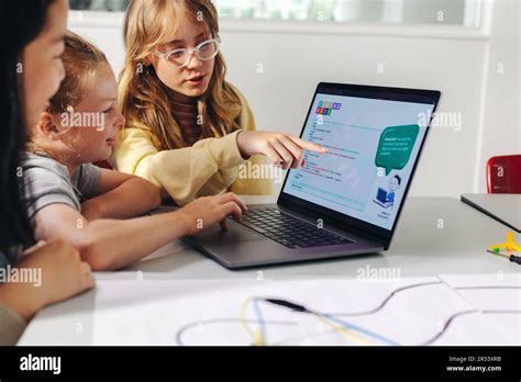 Smart Young Girl Explaining Robot Programming To Classmates In A