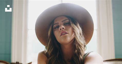 흰색 탱크 탑과 검은 반바지를 입은 여자가 갈색 소파 의자에 앉아 있다 사진 Unsplash의 무료 오스틴 이미지