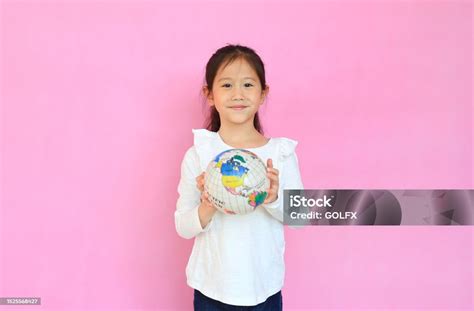 분홍색 배경에 격리된 카메라를 바라보며 지구본을 들고 있는 귀여운 아시아 어린 소녀 지구 지구본을 가진 아이의 초상화 아이들의 얼굴에 초점을 맞춥니다 4 5세에 대한 스톡
