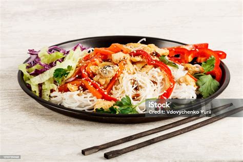 자피 한국 유리 국수 볶음 요리 흰 배경에 참깨 채소와 소스를 곁들인 조림 닭고기를 곁들인 한국유리 자페 국수 맨 위 보기입니다