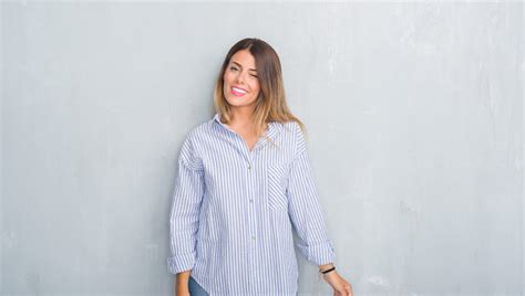 패션 비즈니스 복장 윙크 카메라 섹시 한 표정 명랑 하 고 행복 한 얼굴을 보고 입고 회색 그런 지 벽에 젊은 성인 여자 갈색