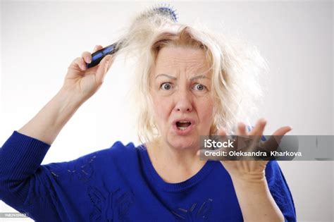 손상된 머리카락 흐트러진 빗을 가진 슬픈 성인 여성은 솔질되지 않은 마른 머리카락을 손에 들고 있는 여성 모델의 초상화를 근접