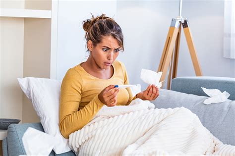 질병 계절 바이러스 문제 개념 온도계의 온도를 보고 소파에 누워 독감에 걸린 여자 고열로 침대에 누워 아픈 여자 감기 독감과 편두통 가정의 방에 대한 스톡 사진 및 기타