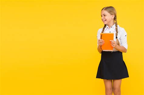 학교 개념으로 돌아갑니다 소녀는 책을 개최합니다 노란색 배경에 학교 소녀 언어를 공부합니다 집에서 공부 교과서와 귀여운 아이 공부 학교 공부를 위한 독서 기술을 연습하고