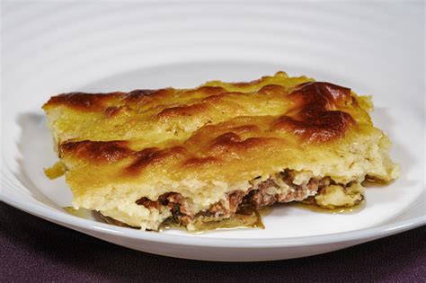 그리스 무사카 요리 레시피 준비 구운 무사카와 베샤멜 화이트 소스 다진 고기 와 가지를 곁들인 다진 감자 튀김을 곁들인 화이트 요리에 대한 준비 된 식사 클로즈업 건강한