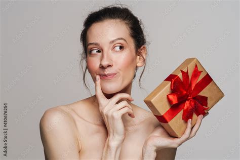 Pleased Half Naked Woman Thinking While Showing Gift Box Stock Photo