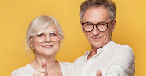 노란 배경에 함께 포즈를 취하는 아름다운 행복한 노부부 확인 기호를 보여줍니다 사진 Unsplash의 남자와 여자 이미지