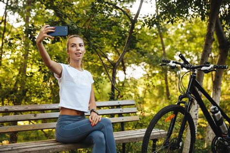 Image Of European Woman Sitting On Bench In Park With Bicycle And