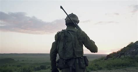 Военный с рюкзаком и боеприпасами идет со снайперской винтовкой