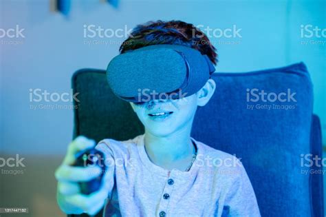 네온 라이트 효과와 함께 보여주는 소파에 앉아있는 동안 Vr 또는 가상 현실 헤드셋과 게임 패드를 착용하여 게임을 하는 어린