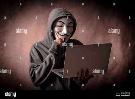 Hacker With Anonymous Mask With A Laptop Thinking About Programming Studio Shot Stock Photo Alamy