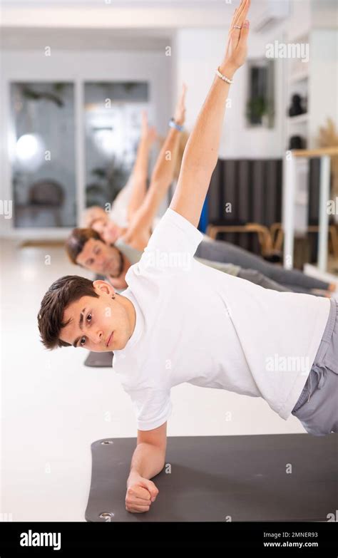 Women And Men Exercising Yoga Poses In Fitness Center Extended