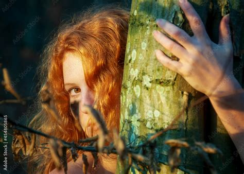 Portrait Of Beautiful Sexy Babe Woman Redhead Hugging Tree Trunk In Forest With Friendly Smile